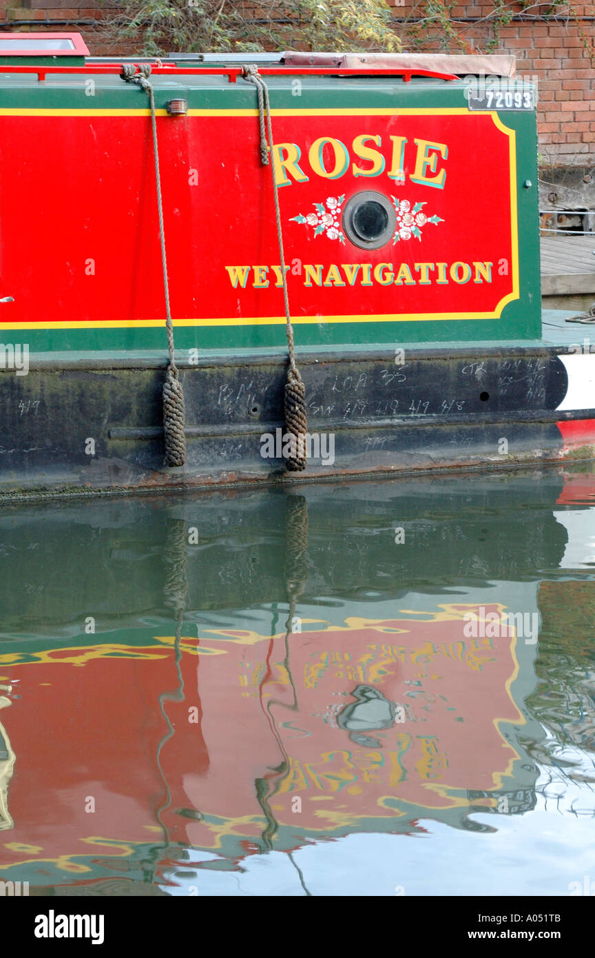 Bright red and green narrowboat barge reflected in the canal, Regent's ...