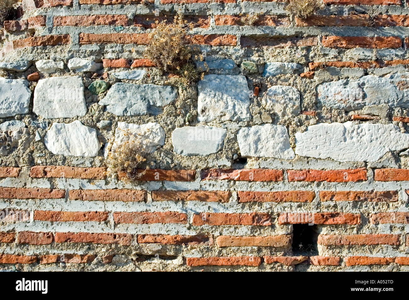 An ancient old rough drystone masonry and terracotta brick wall, Saint ...