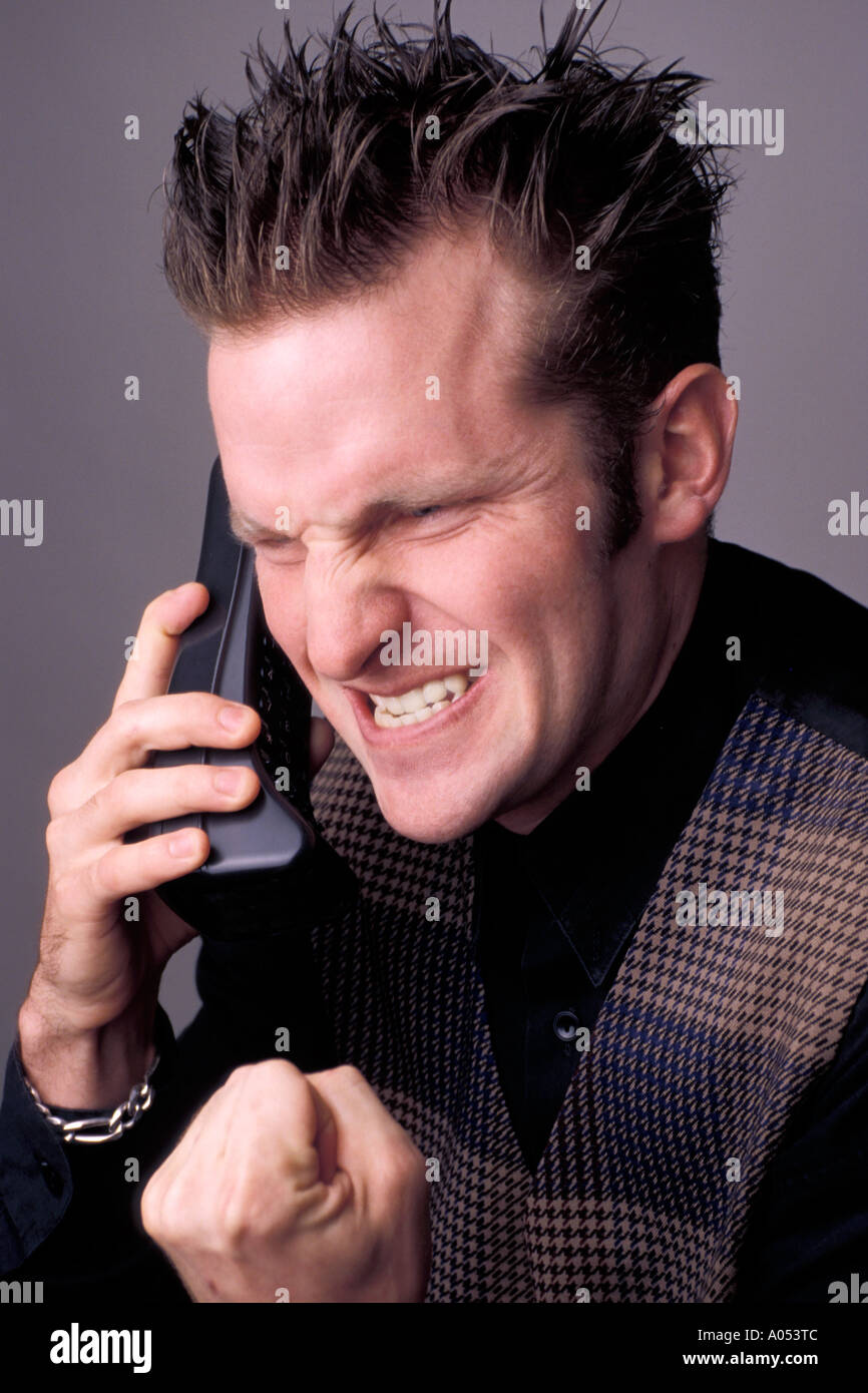 angry man on phone with hands clenched into a fist and snarling look on ...