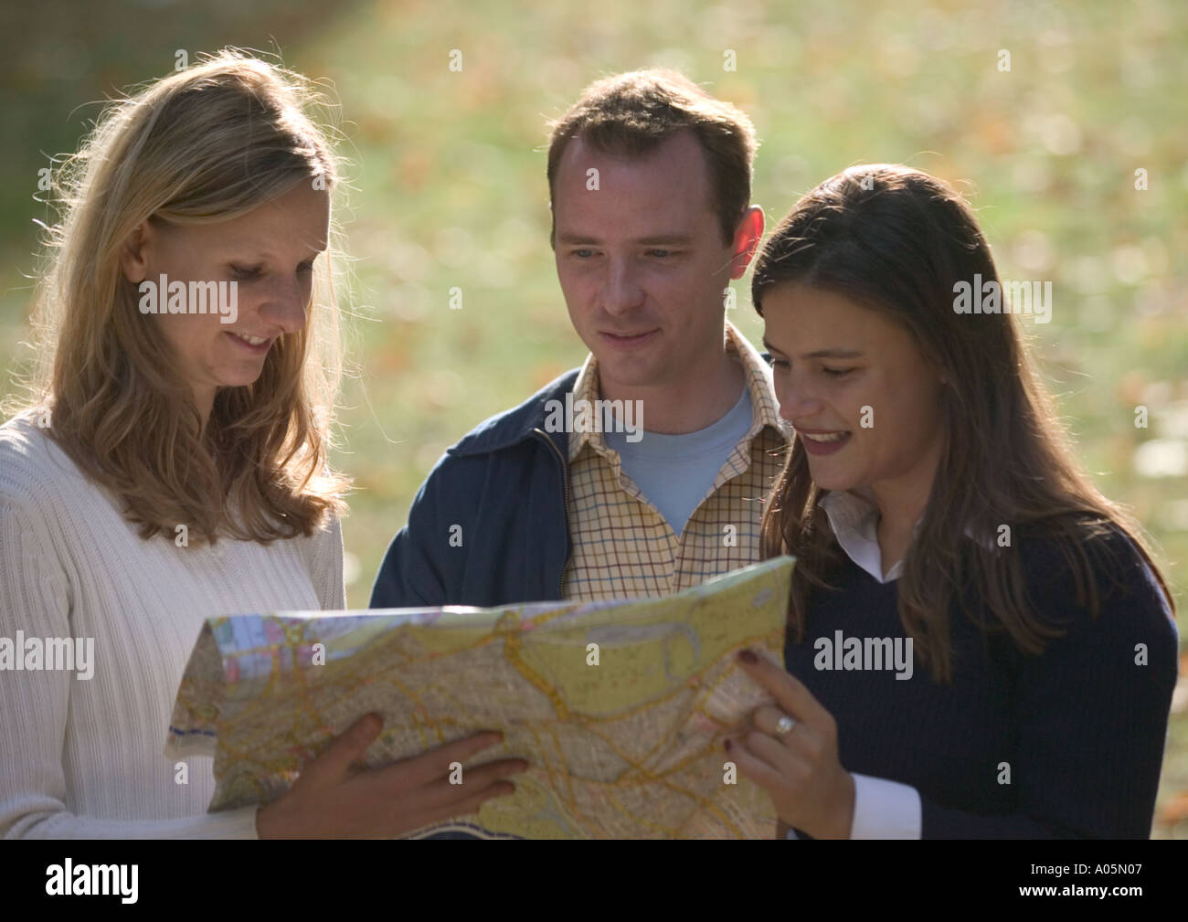 two girls and boy studying map Stock Photo - Alamy