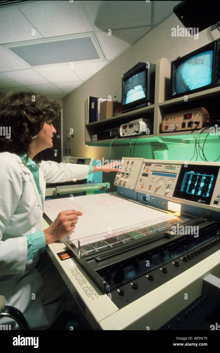 Female sleep therapist monitors EEG activity in a sleep laboratory ...