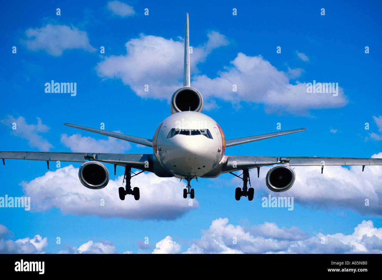 CD 10 jet airplane flying directly at camera with blue sky and clouds ...