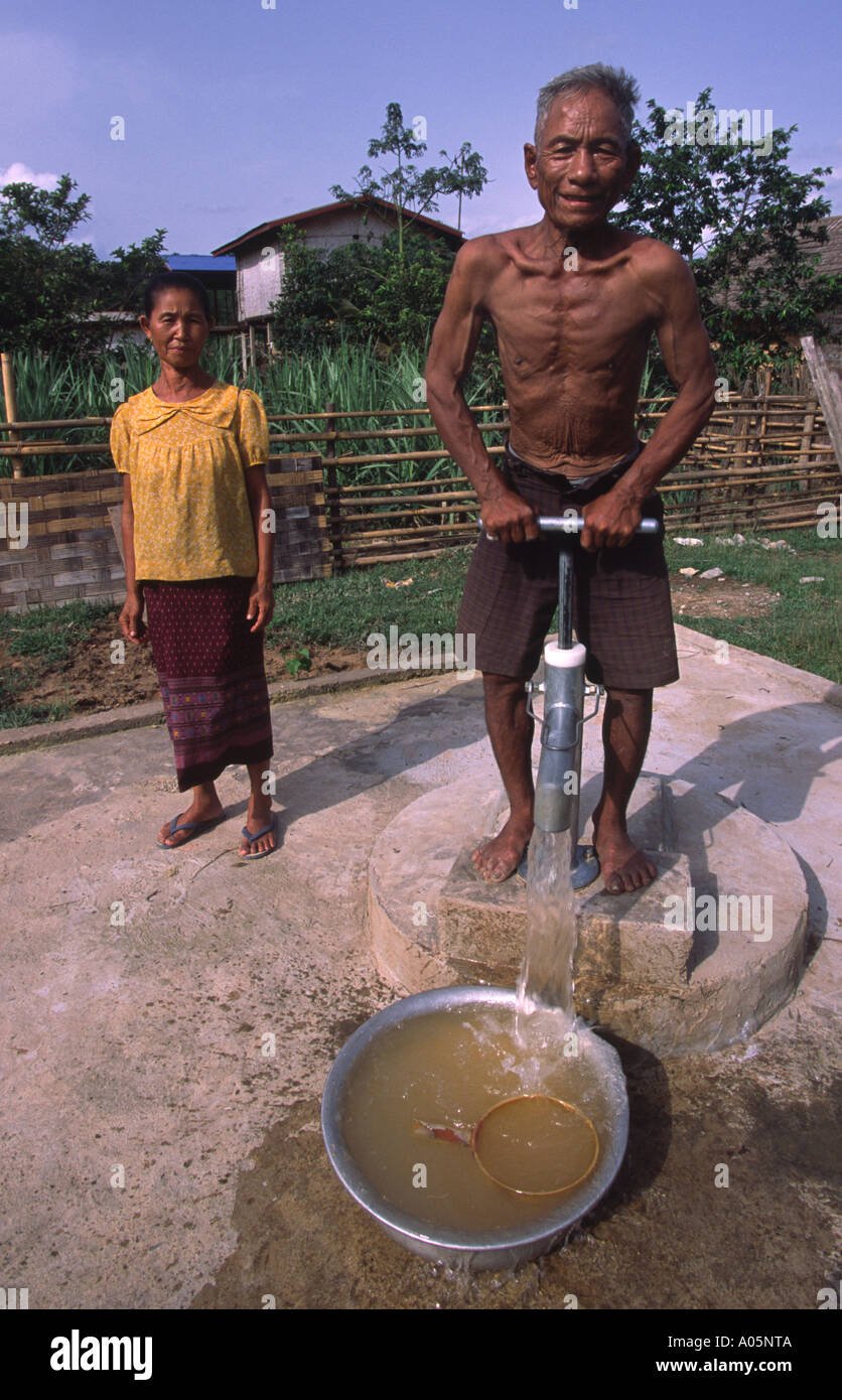 Old man pumping water with a pump provided by an aid organization. Near ...