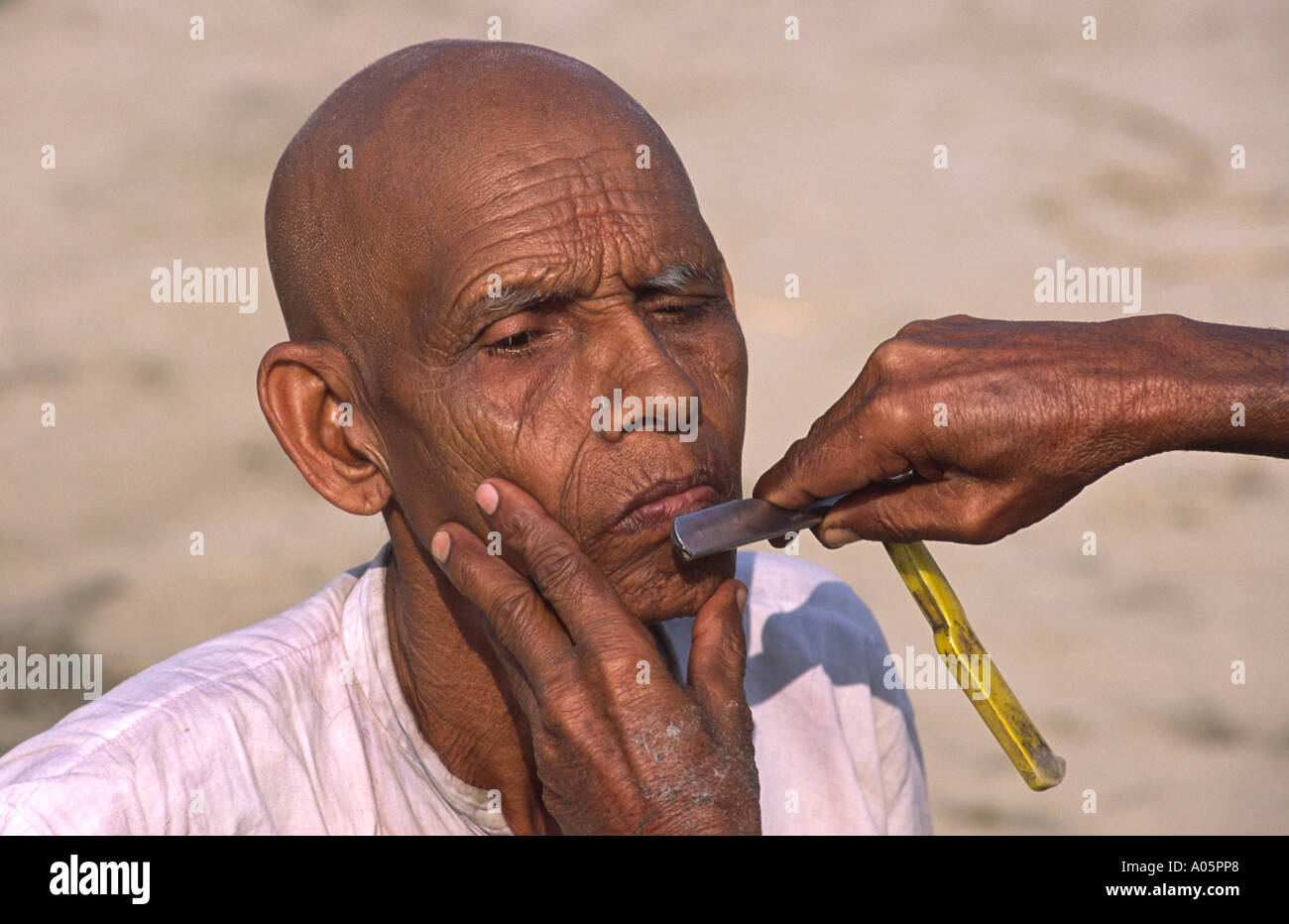 Hindu Pilgrim getting a shave before Ganges bath. Khumb Mela festival ...