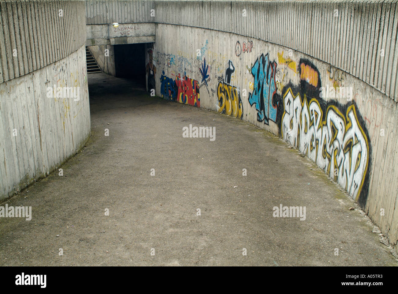 Slope leading to a subway with colourful graffiti spayed onto the walls ...