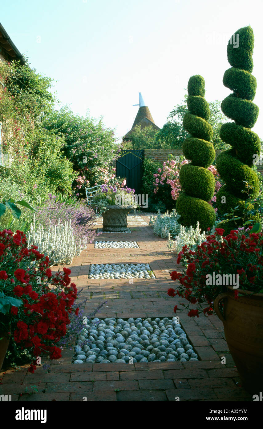 Pebble and brick path with corkscrew topiary in Cabbages and Kings ...