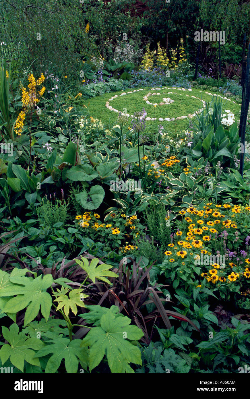 Spiral paving in circular lawn with yellow rudbeckia in foreground ...