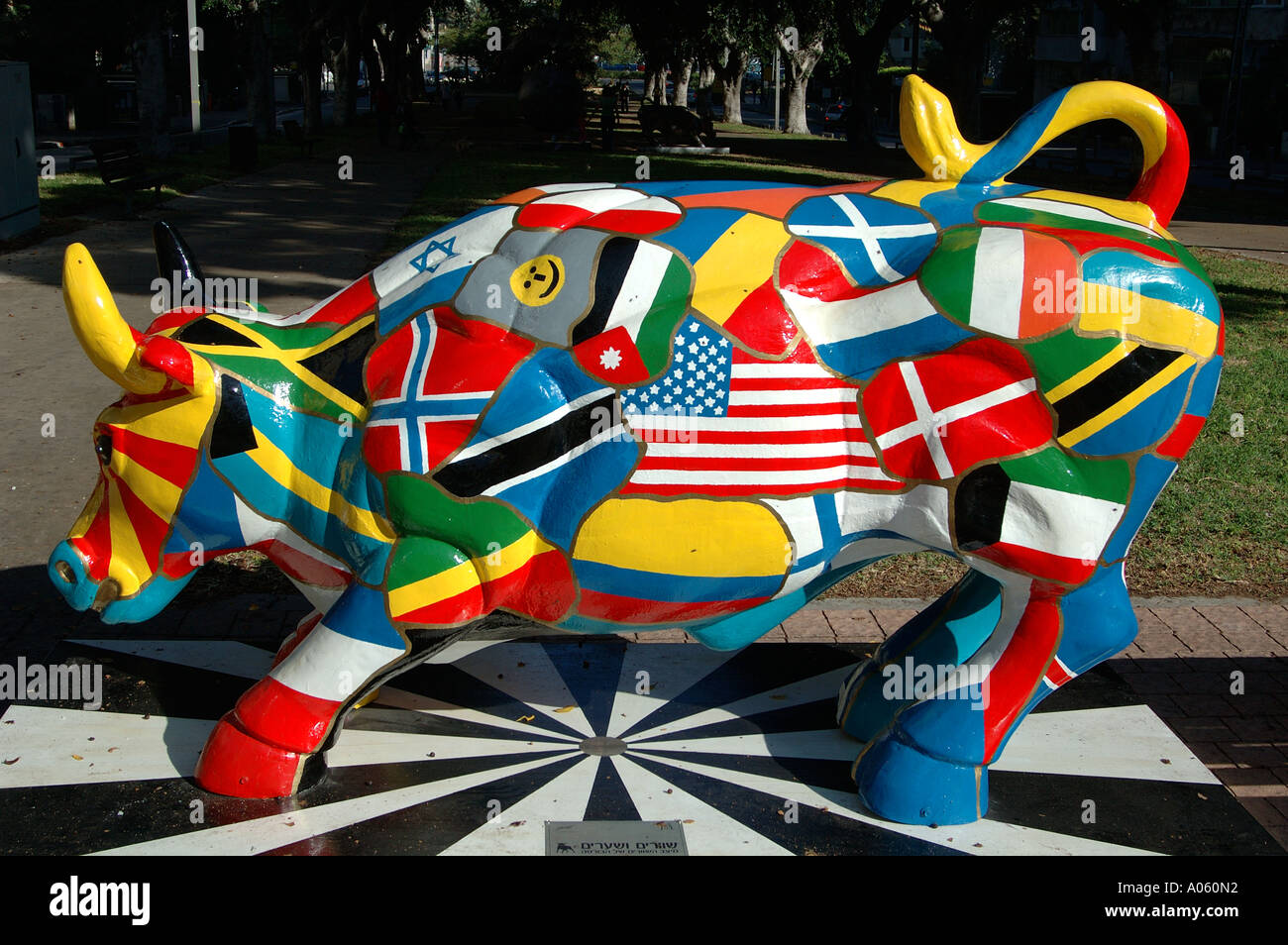 A statue of a bull painted in the colors of different national flags ...