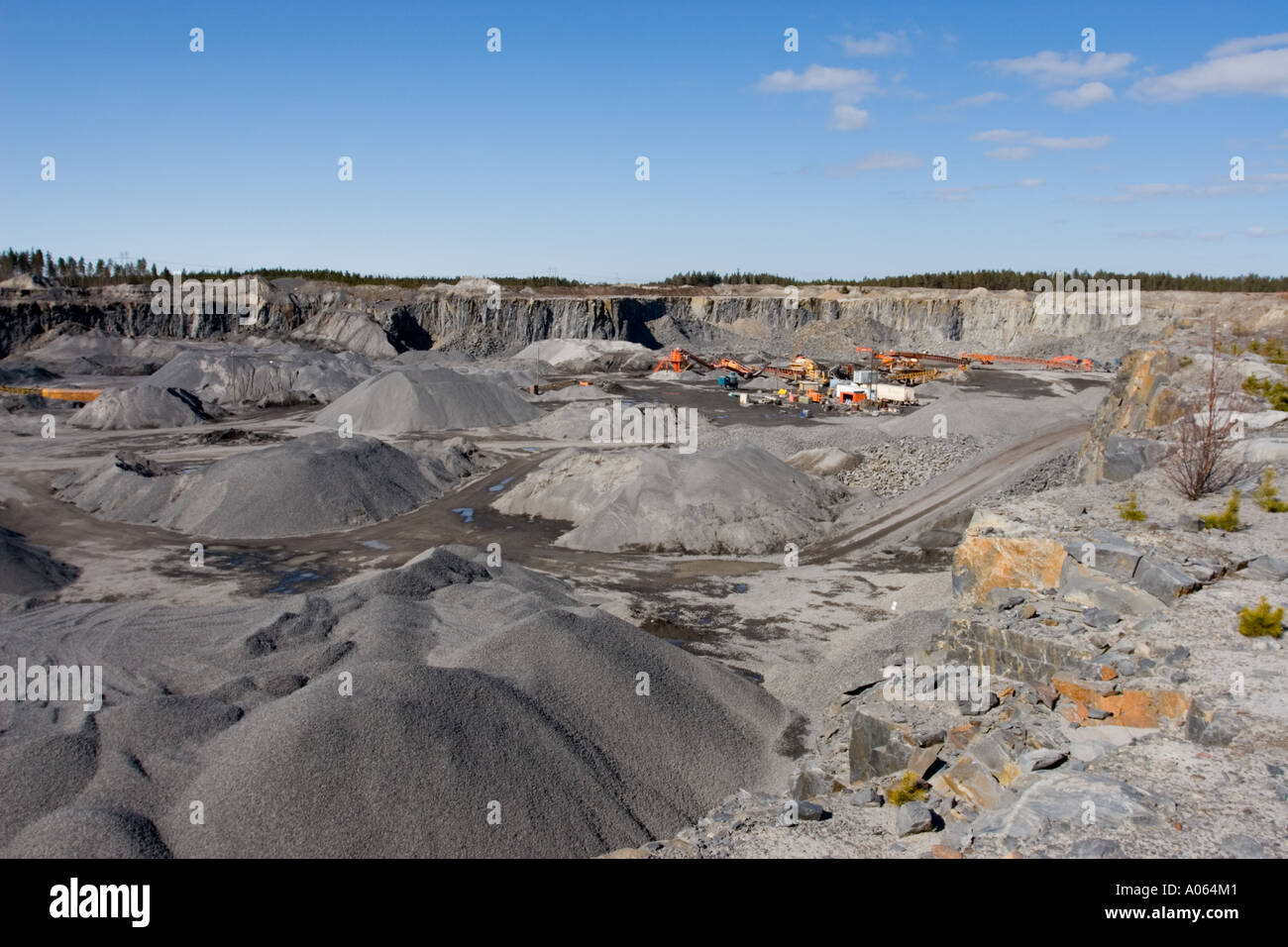 Machinery and piles of fine gravel a the bottom of a rock quarry ...
