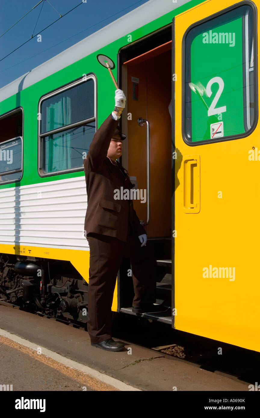 Train guard or conductor standing behind yellow green train showing ...
