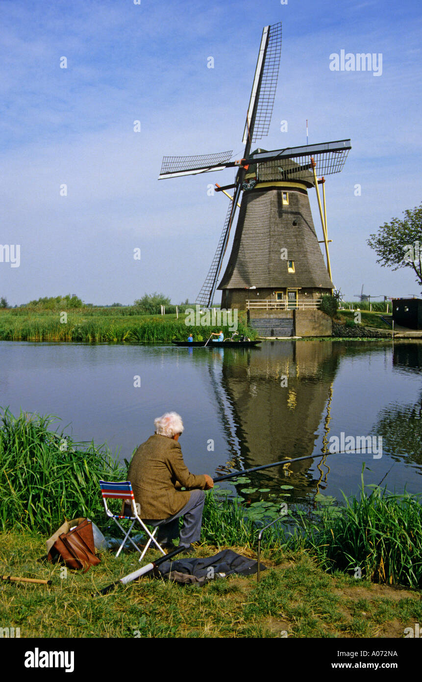 Fisherman at canal with windmill Holland Netherlands Europe Stock Photo ...