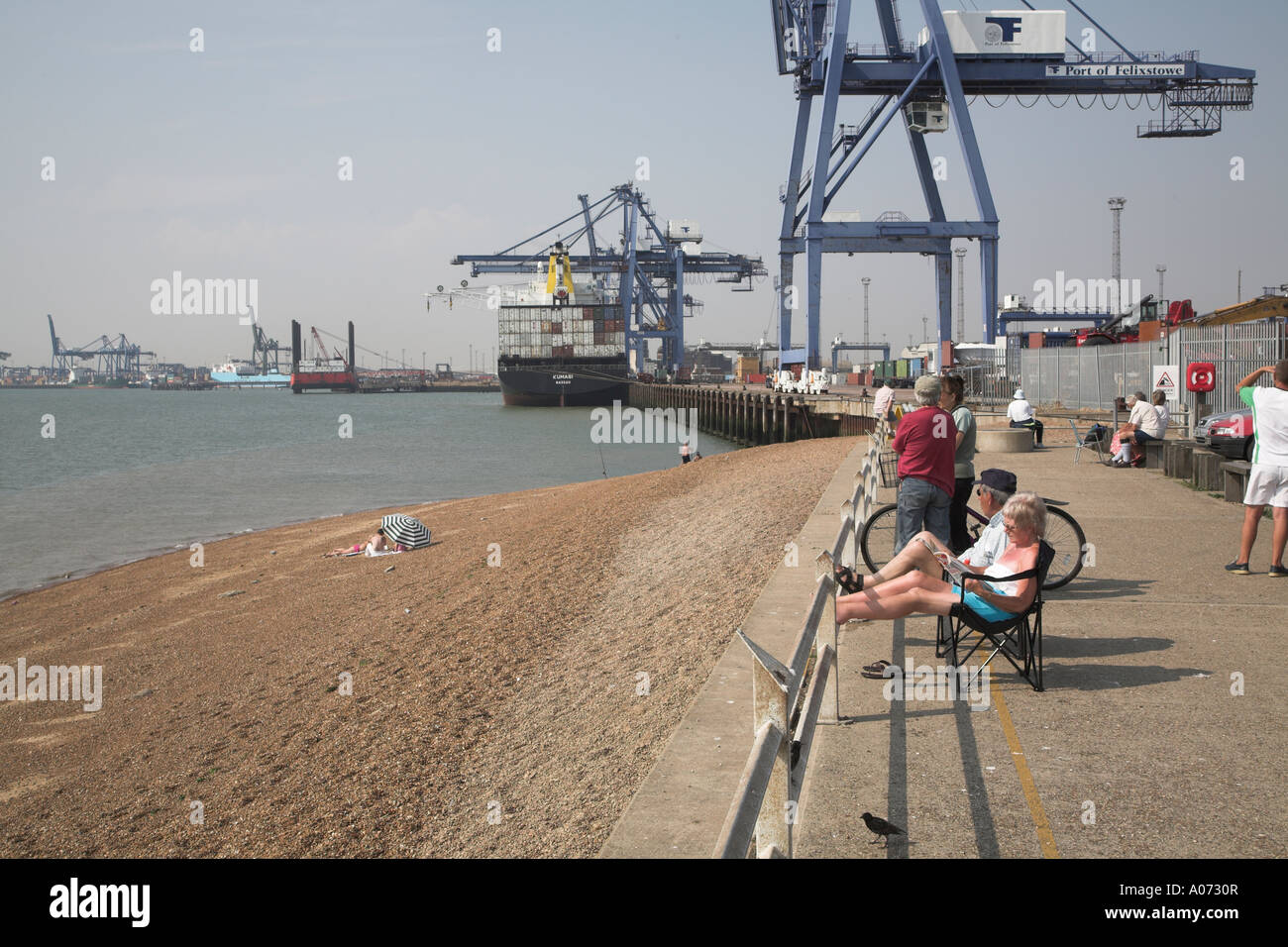 Container ship and cranes Felixstowe docks with people on the beach and ...