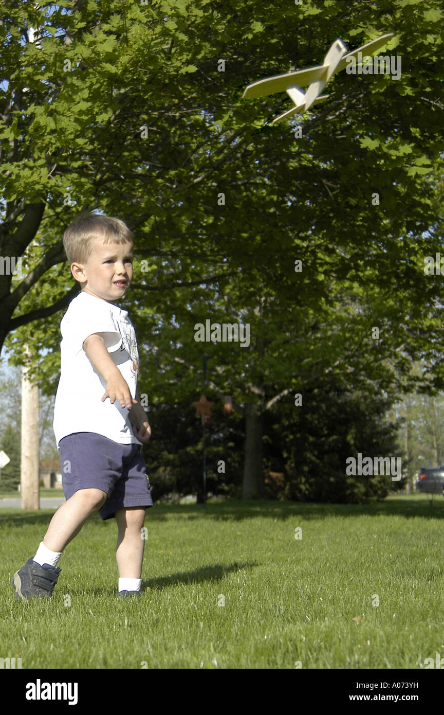 4 year old caucasian boy flies balsa wood glider in front of tree Stock ...