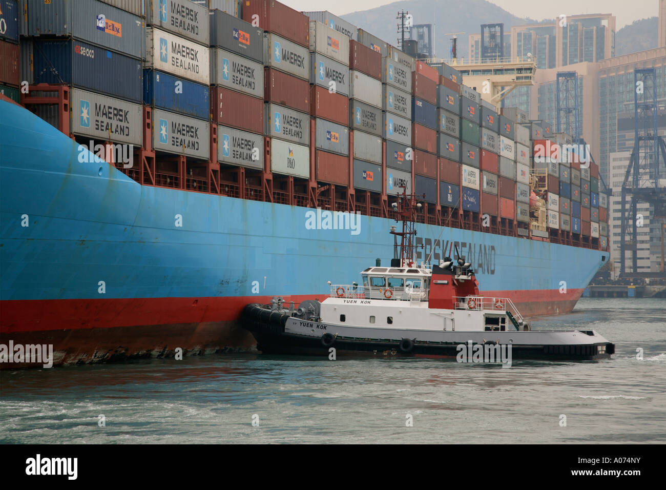 Tugboats manoevering around an ocean going containership at kwai chung ...