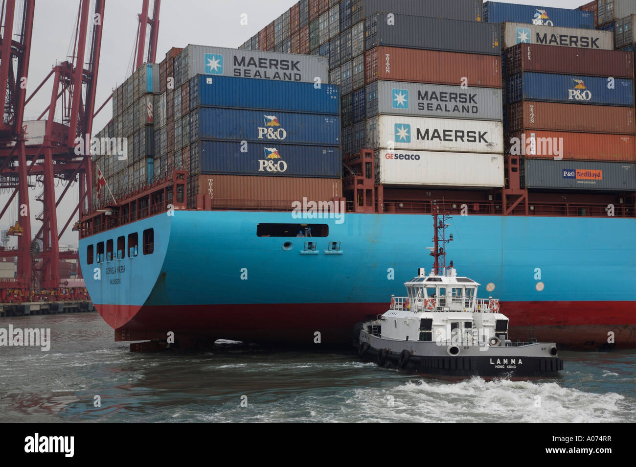 Tugboats manoevering around an ocean going containership at kwai chung ...