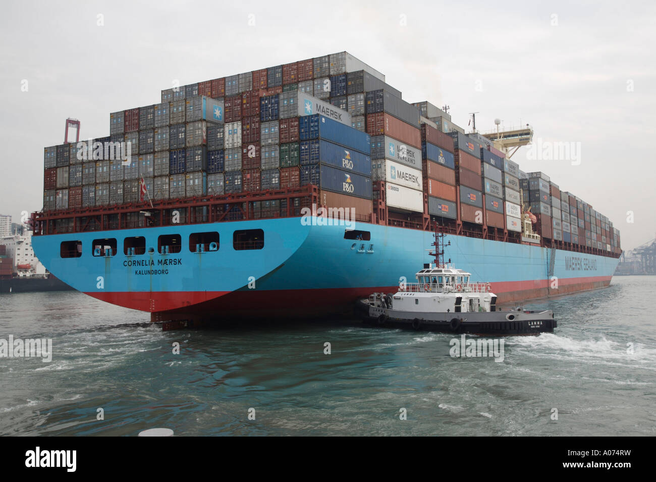 Tugboats manoevering around an ocean going containership at kwai chung ...