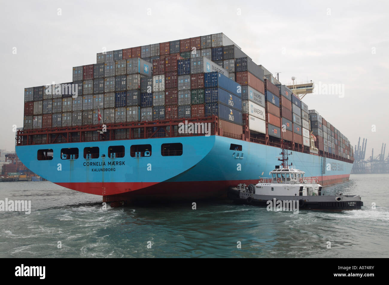Tugboats manoevering around an ocean going containership at kwai chung ...