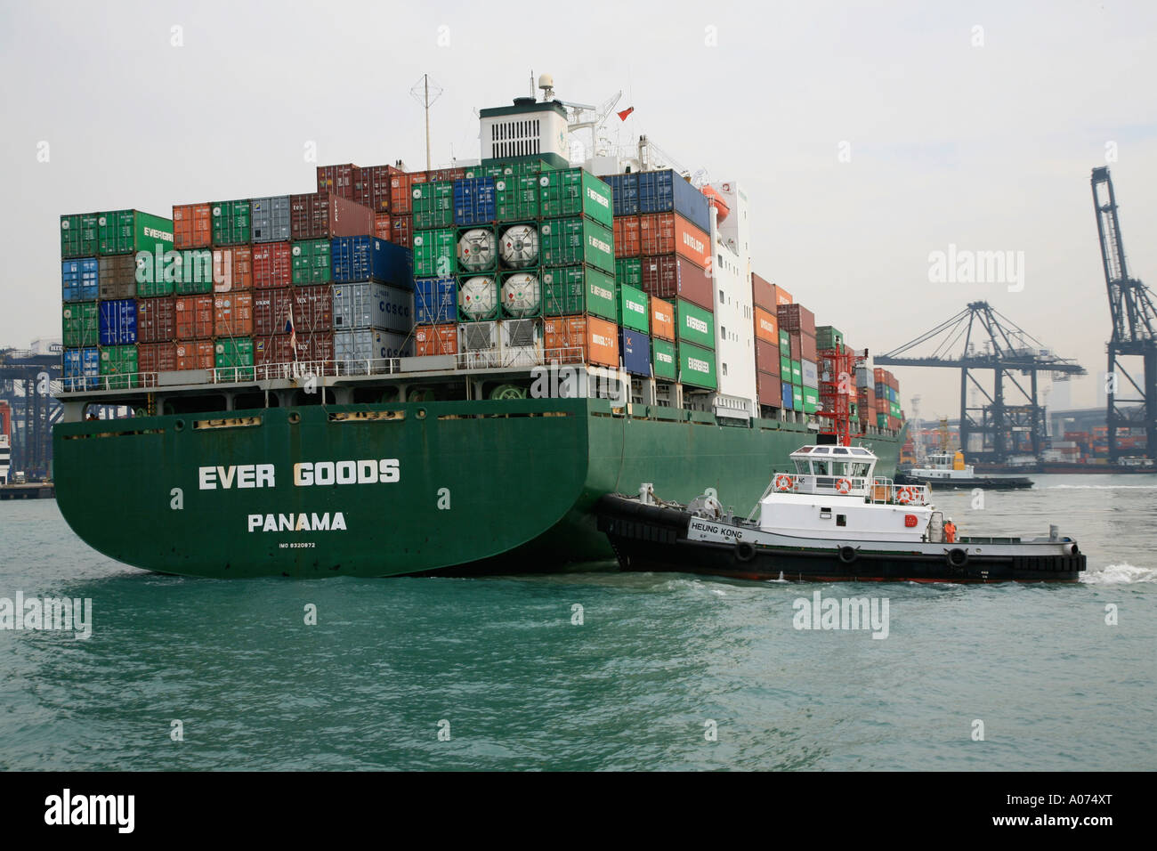 Tugboats manoevering around an ocean going containership at kwai chung ...