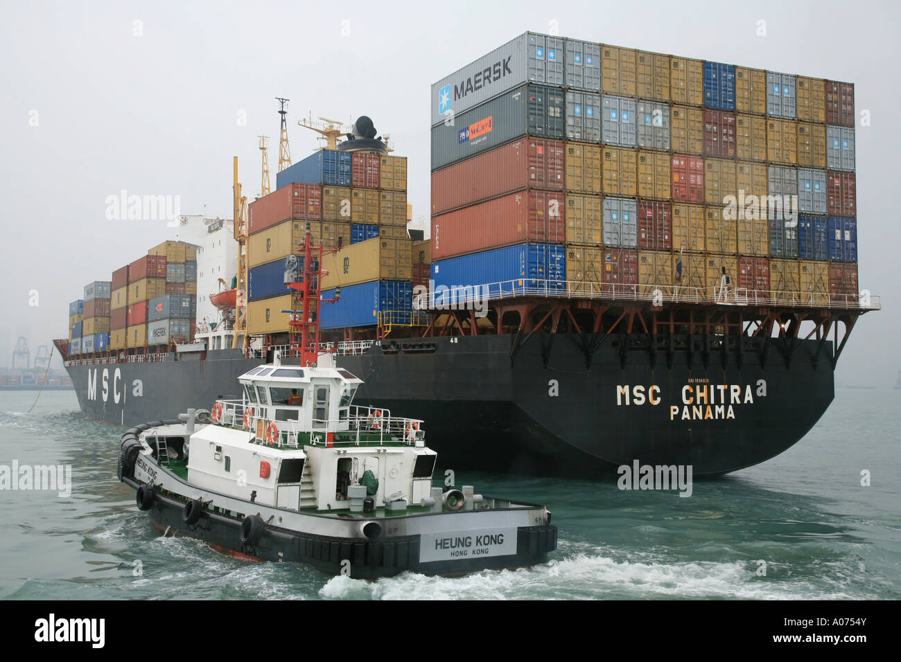 Tugboats manoevering around an ocean going containership at kwai chung ...