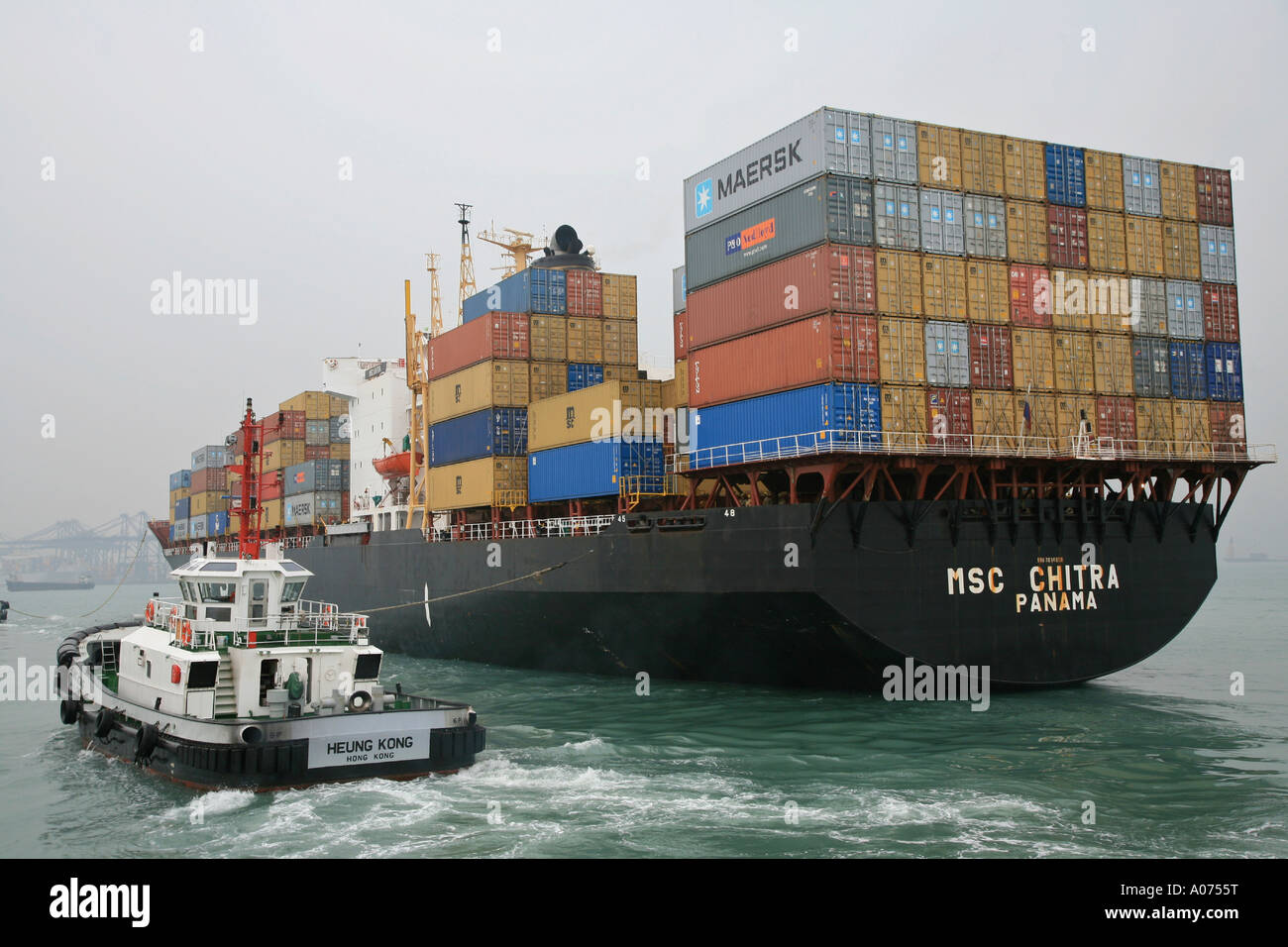 Tugboats manoevering around an ocean going containership at kwai chung ...