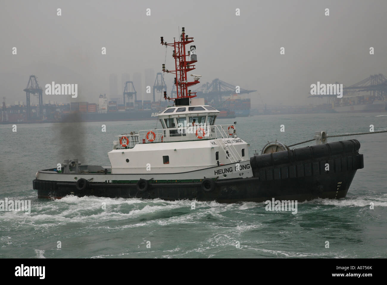 Tugboat manoevering in Kwai Chung by a container ship in Container Port ...