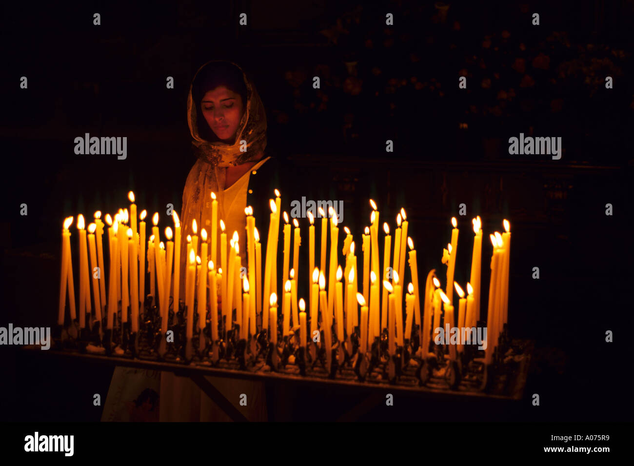 A woman lighting prayer candles inside a Catholic Church in Italy Stock ...
