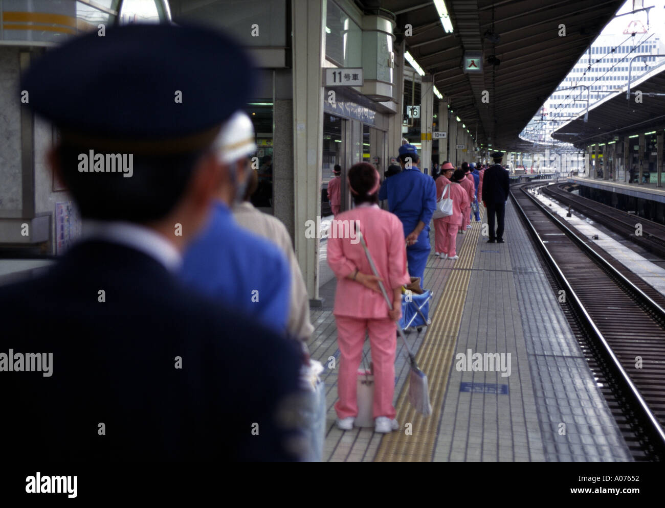 Japanese Train guards and cleaners await the arrival of a Bullet Train ...