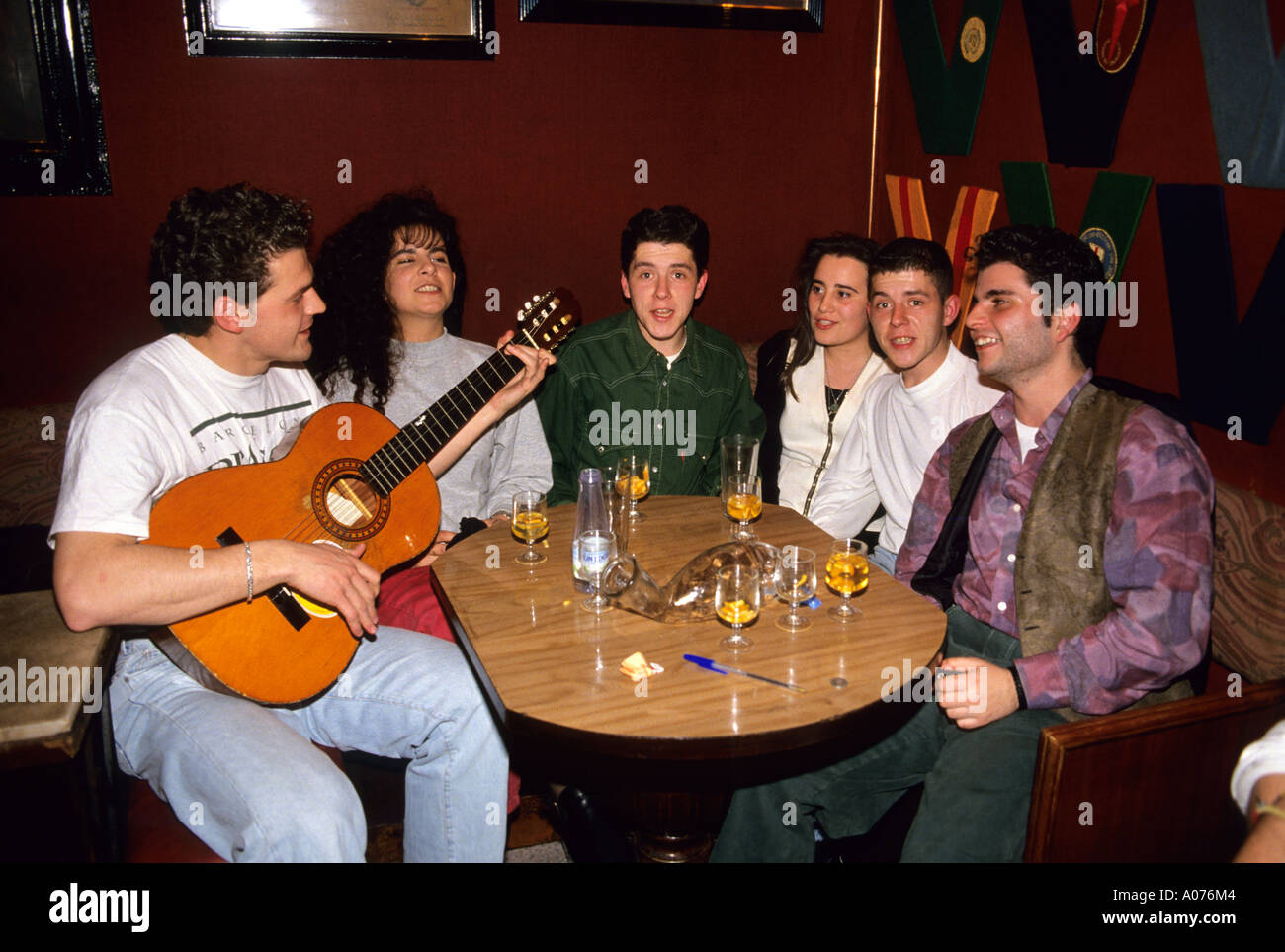 Spanish college students sing along to a guitar being played at a club ...