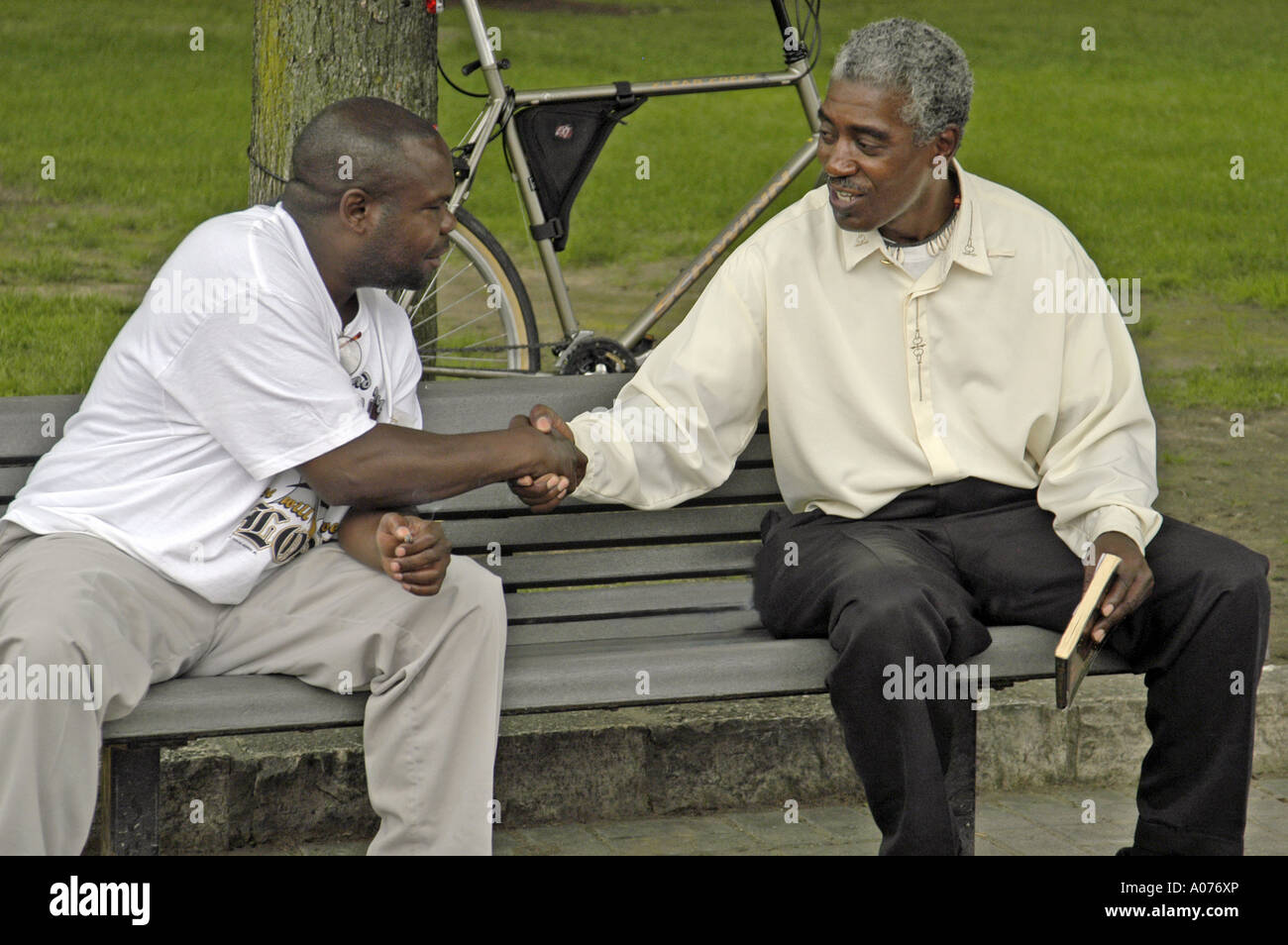 P23 080 Two Black Men Shake Hands On Park Bench MR Stock Photo - Alamy