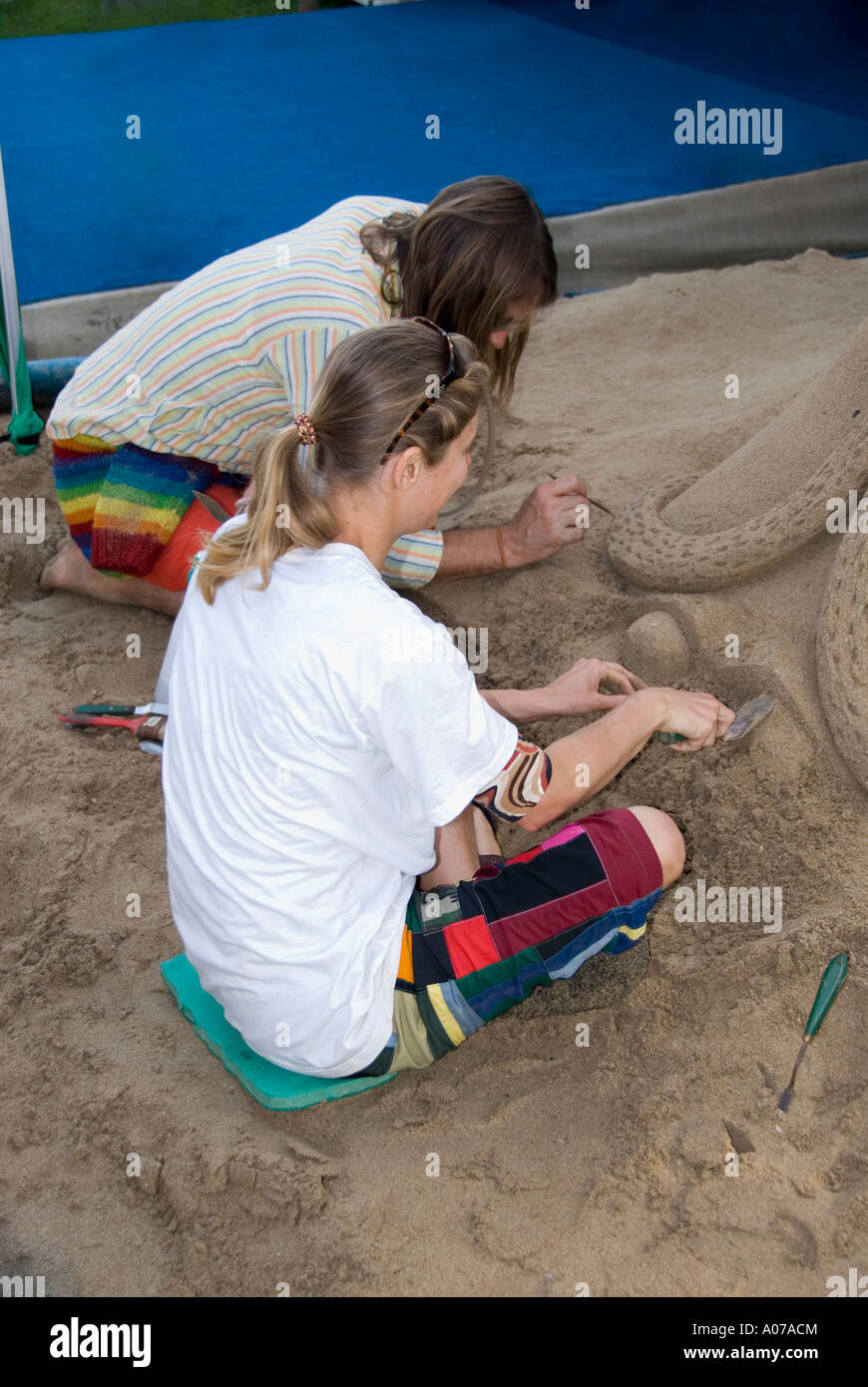 Women kneel in sand pit indoors demonstrating sand sculpture at Royal ...