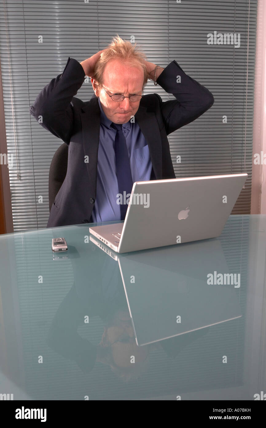 Businessman using a laptop computer looking stressed and holding his ...