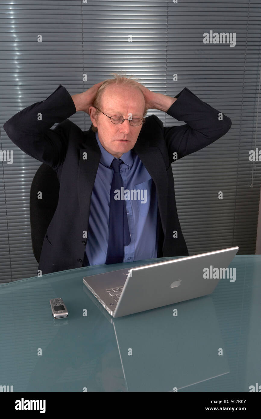Businessman using a laptop computer looking stressed and holding his ...