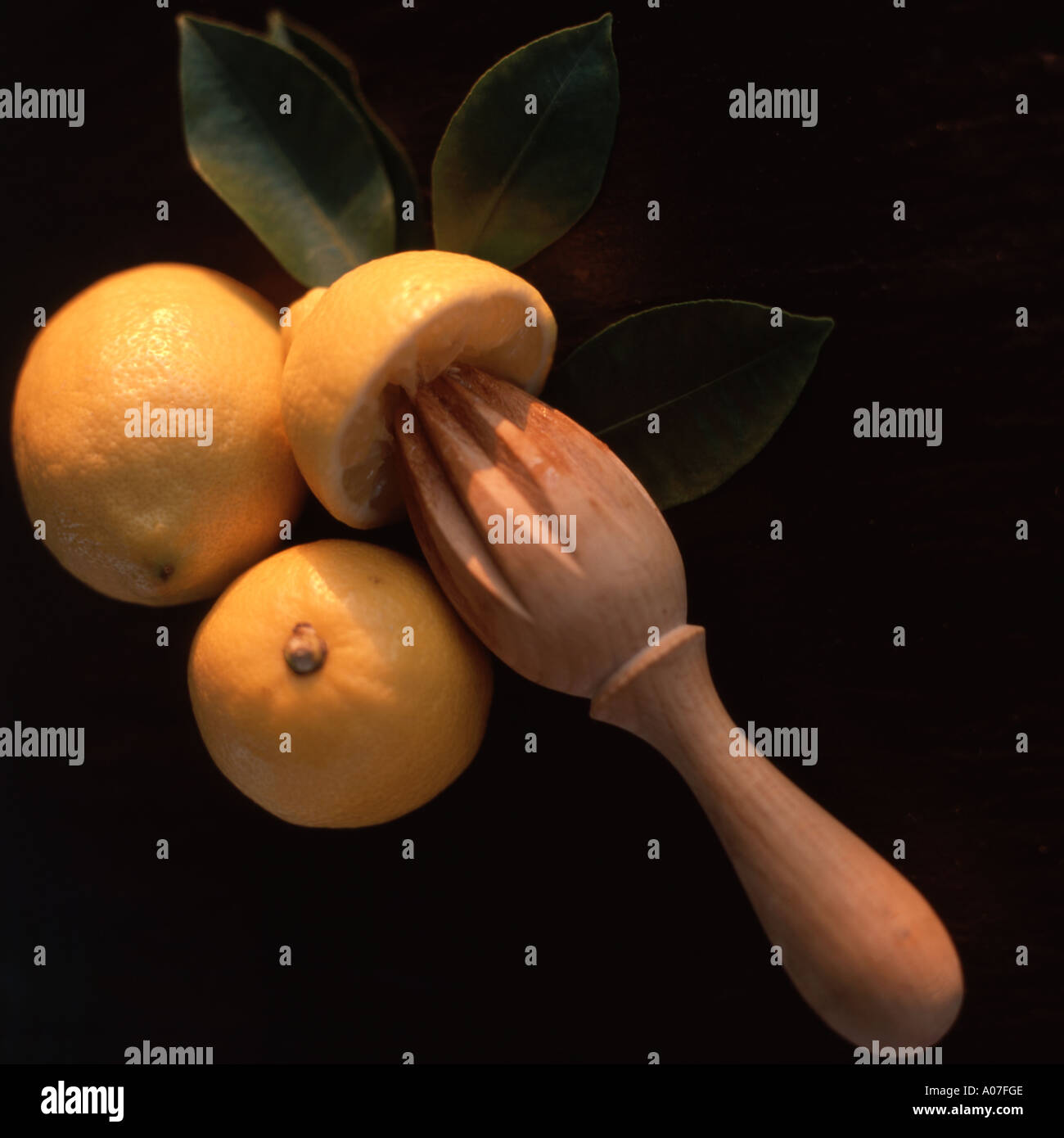 Traditional wooden lemon squeezer with fresh lemons and leaves slate ...