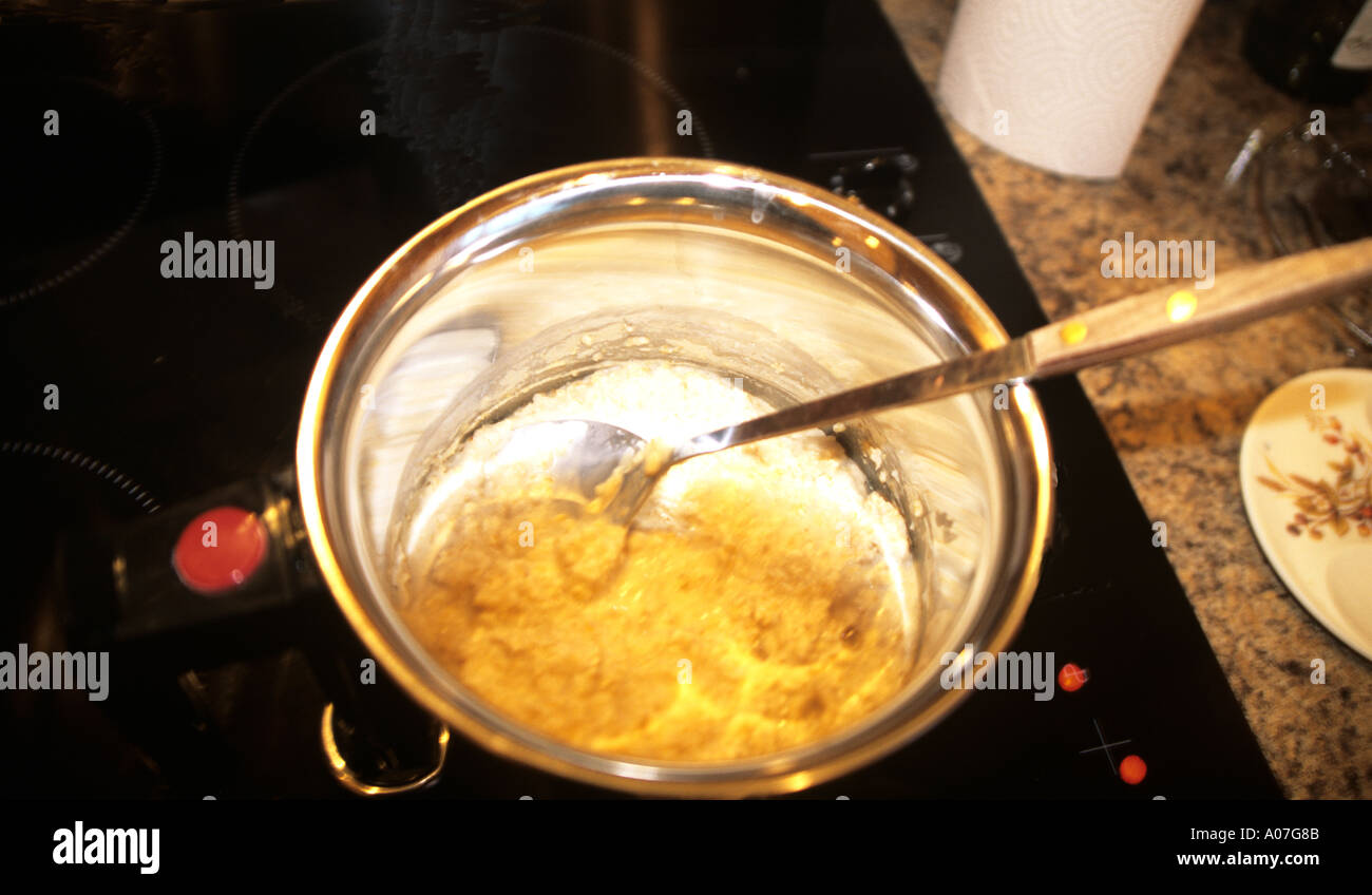 STILL LIFE A metal spoon in a saucepan with the contents starting to ...