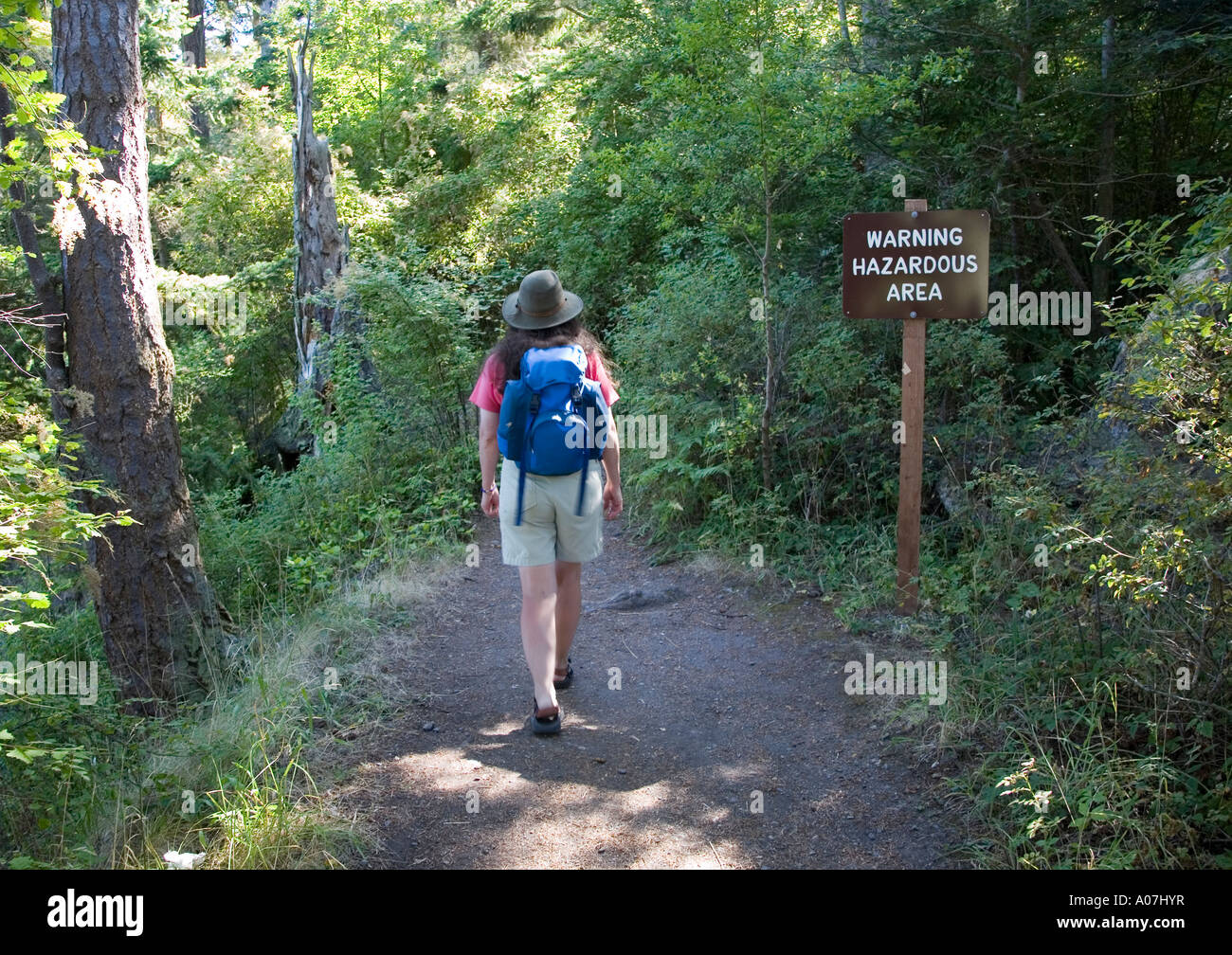 Woman hiker walking past sign warning harzardous area Deception Pass ...