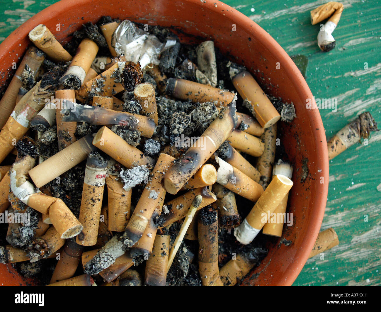 full ashtray on linoleum surface Stock Photo - Alamy