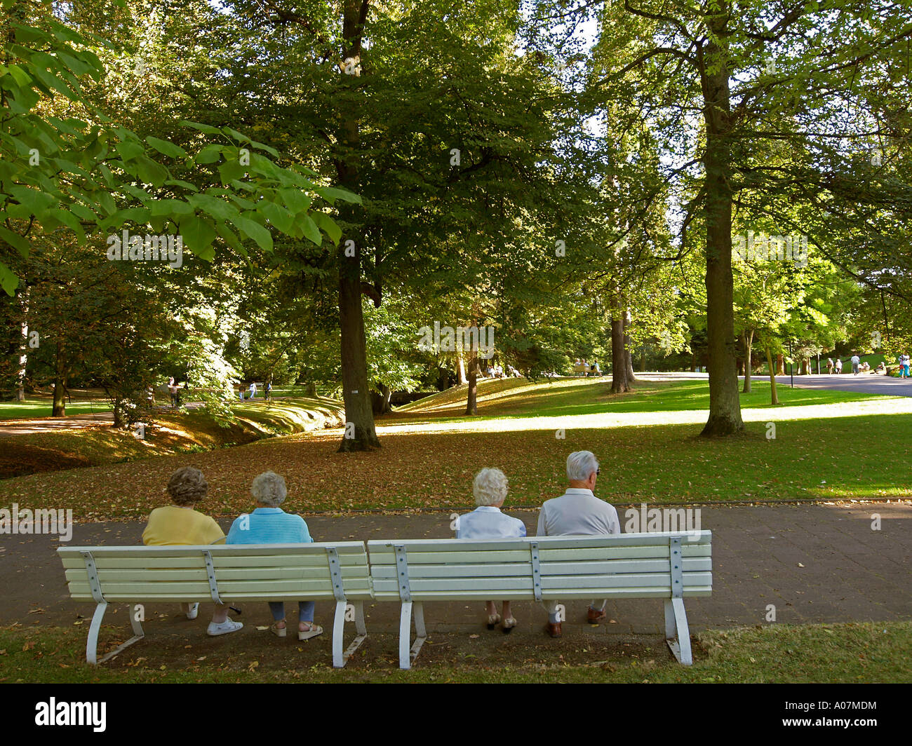 senior citizens old age pensioners OAP sitting on a bench in park a ...