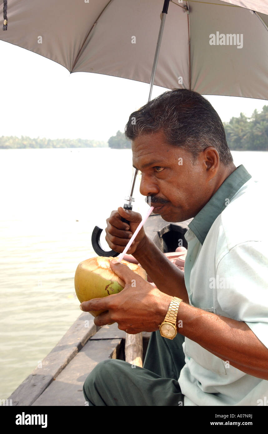 Houseboat skipper drinks coconut milk as he steers boat through the ...