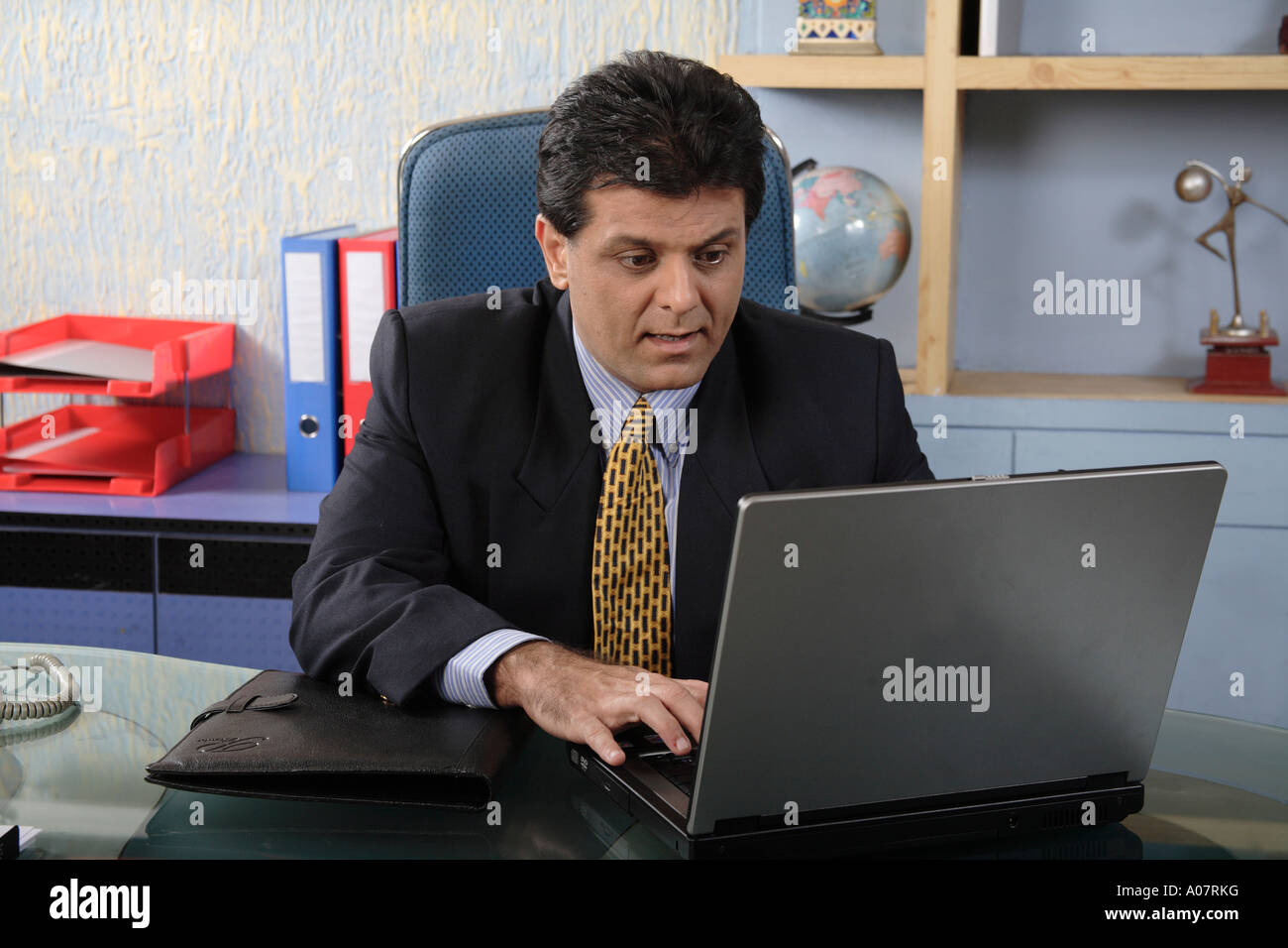CEO sitting working on computer in his office cabin in business suit ...