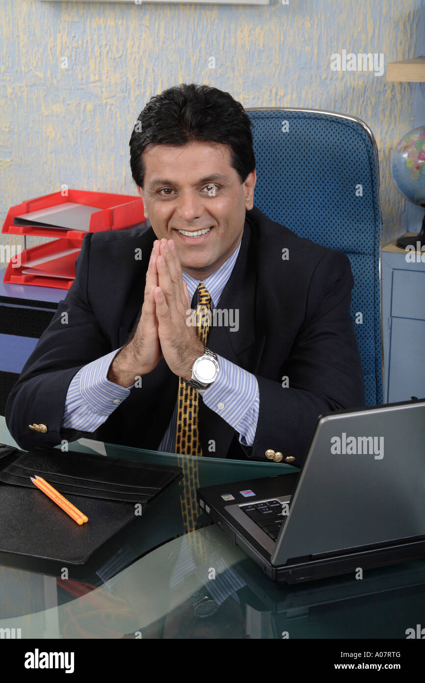 CEO with folded hands saying namaste in his office cabin in business ...