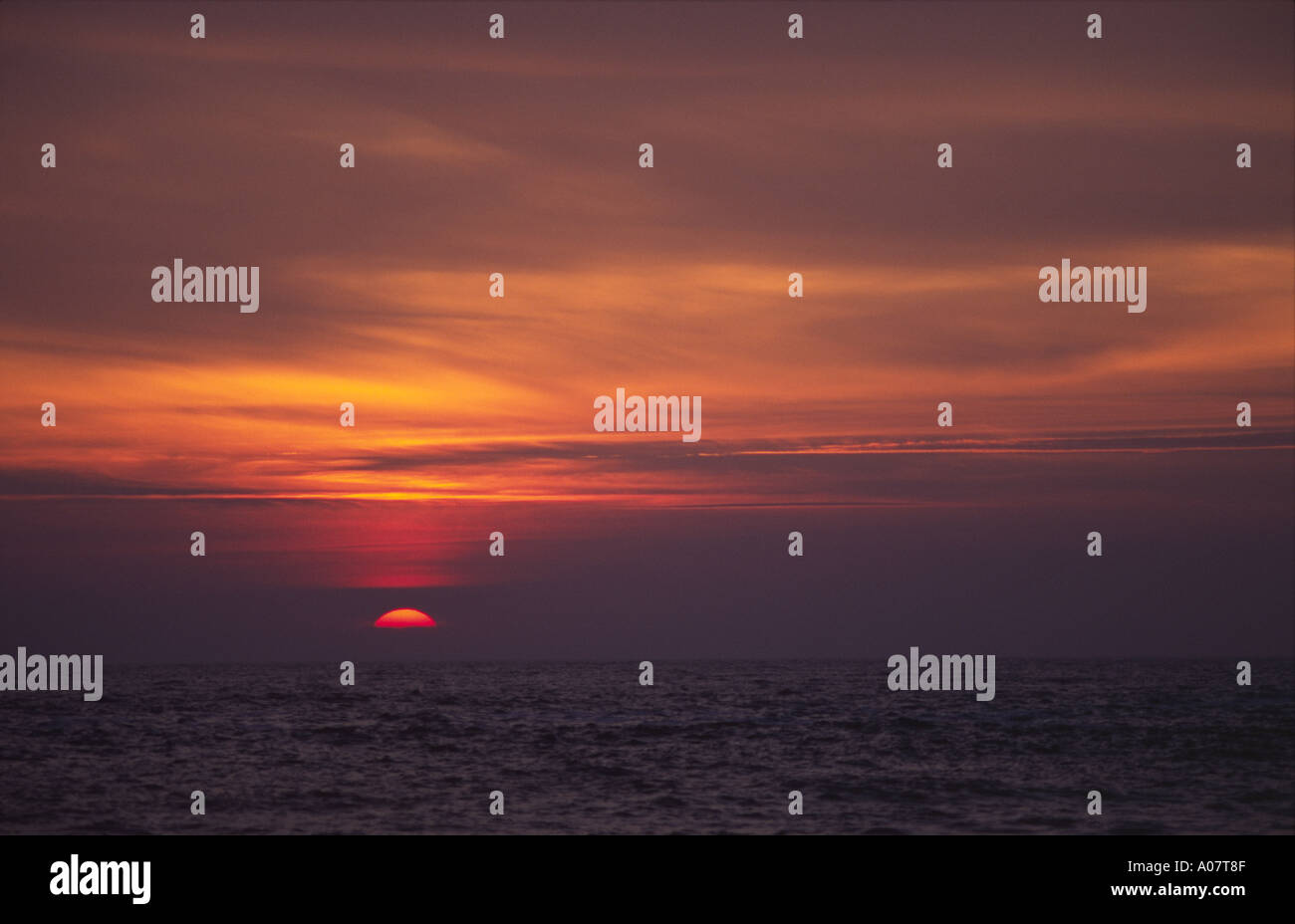 Sun setting into the sea Stock Photo - Alamy