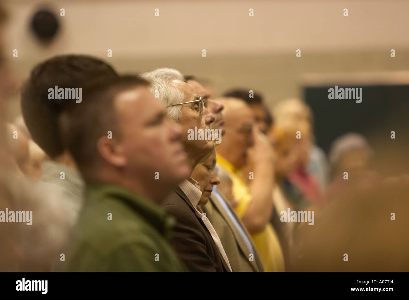 A crowd of people looking somber at a memorial service after a death ...