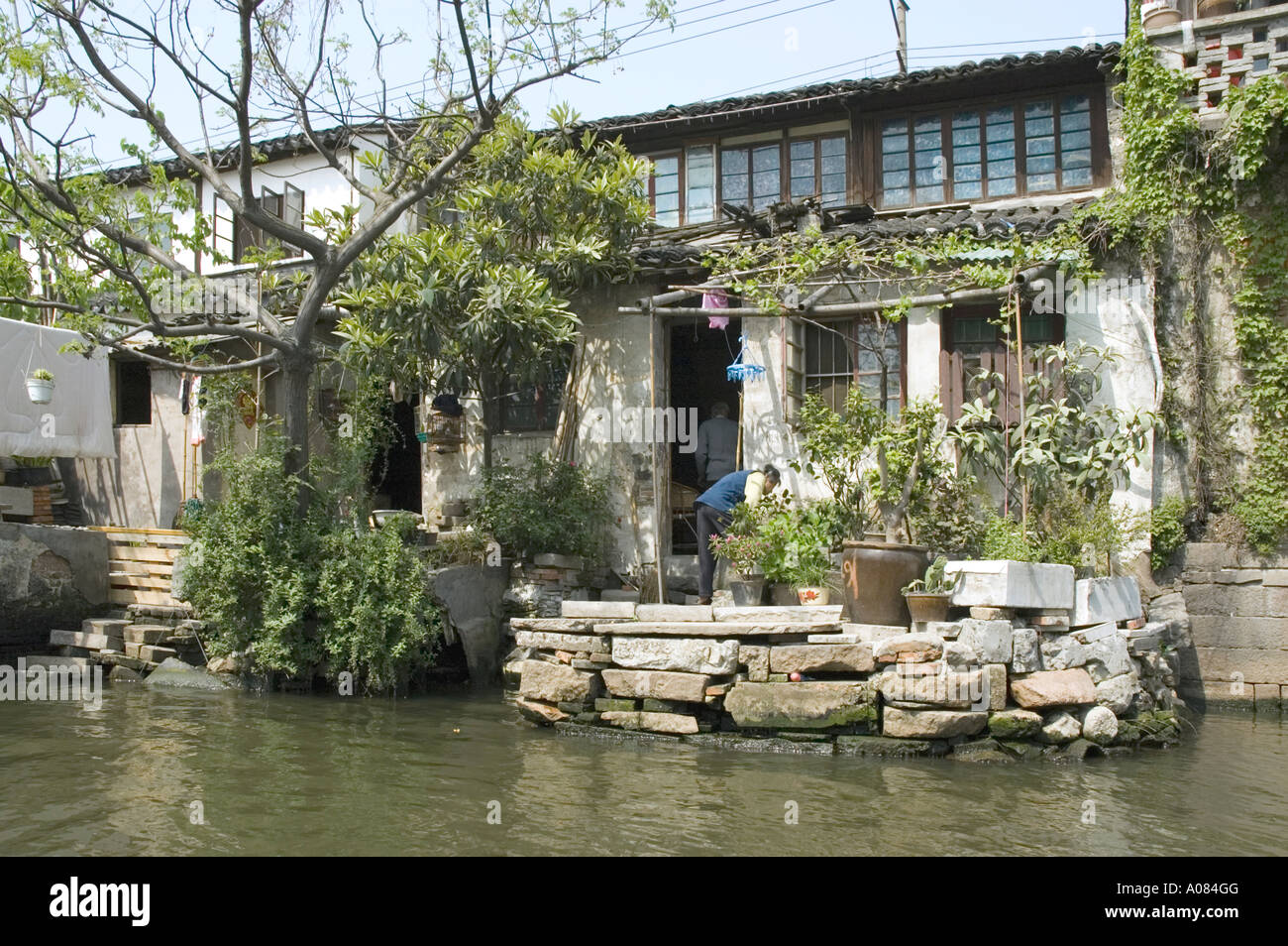 A traditional two storey old house with a Chinese resident tending the ...