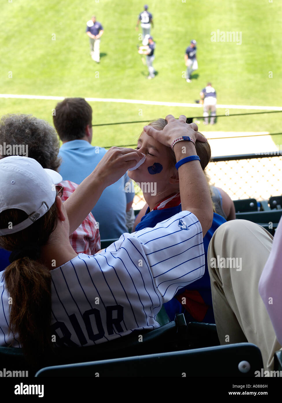 Mother applies face paint on her daughter as they wait for baseball ...