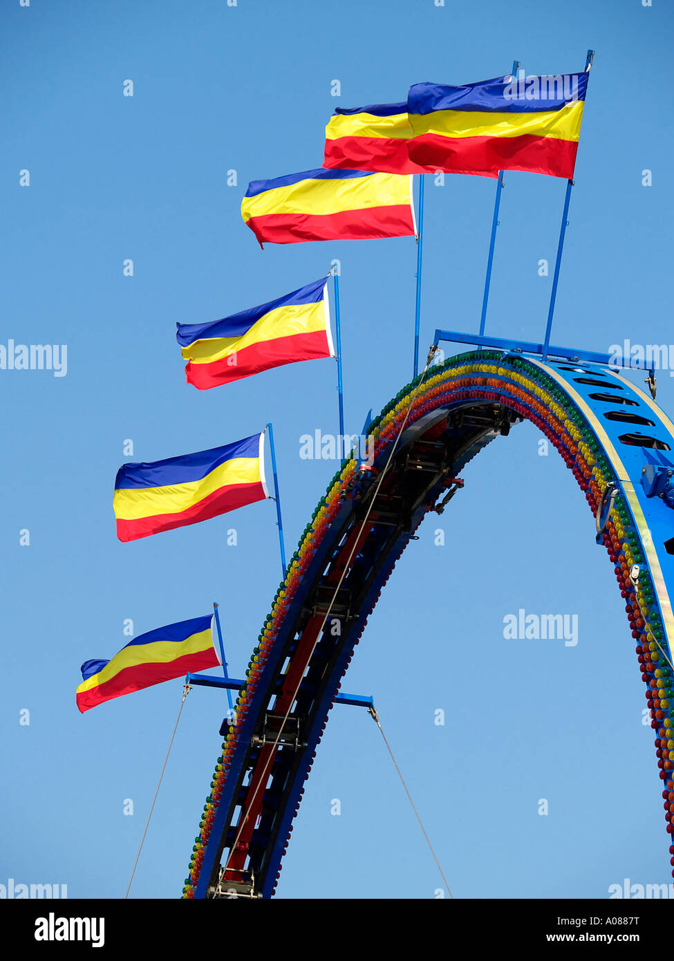 Colorful flags atop a roller coaster at a summer carnival with the deep ...