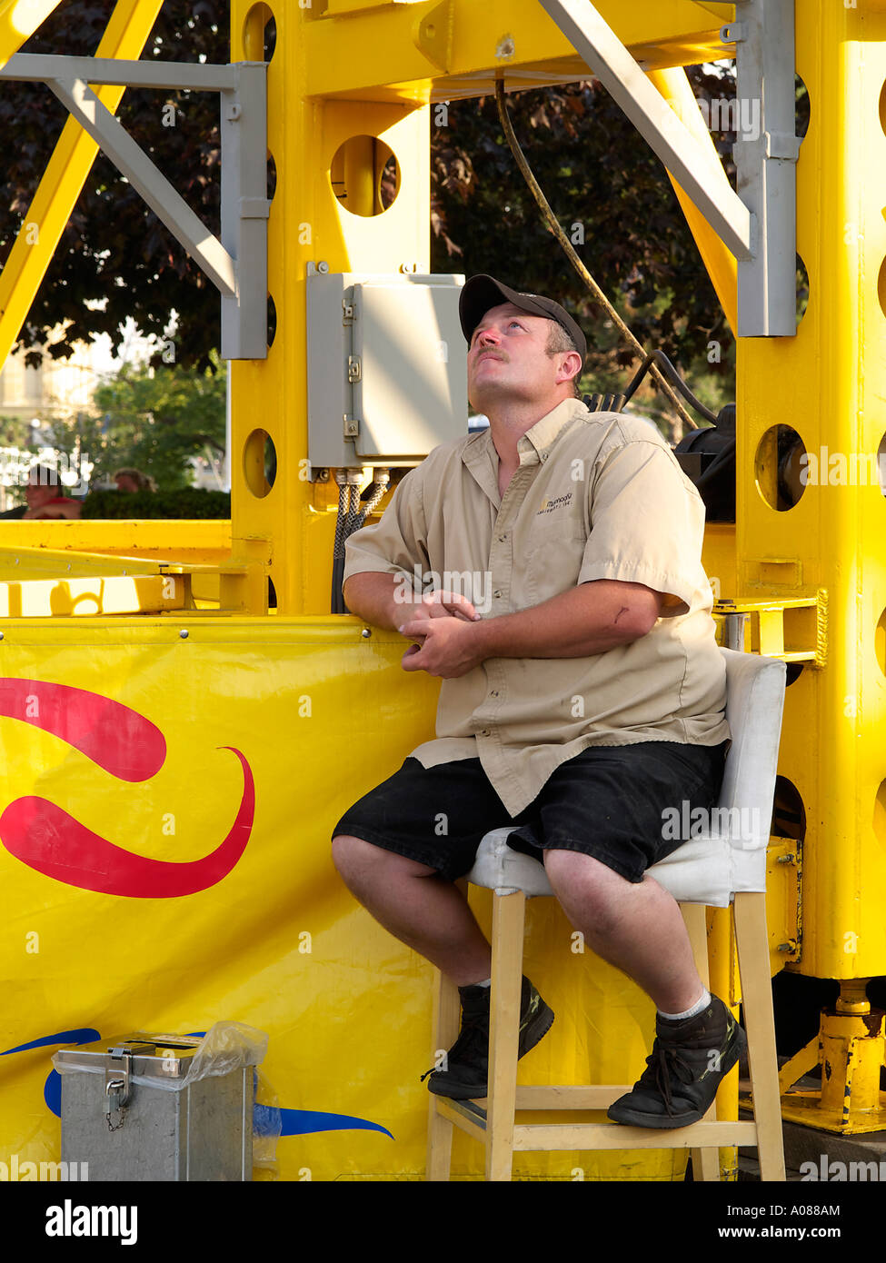 Carnival worker attends to the ferris wheel keeping a close eye on his ...