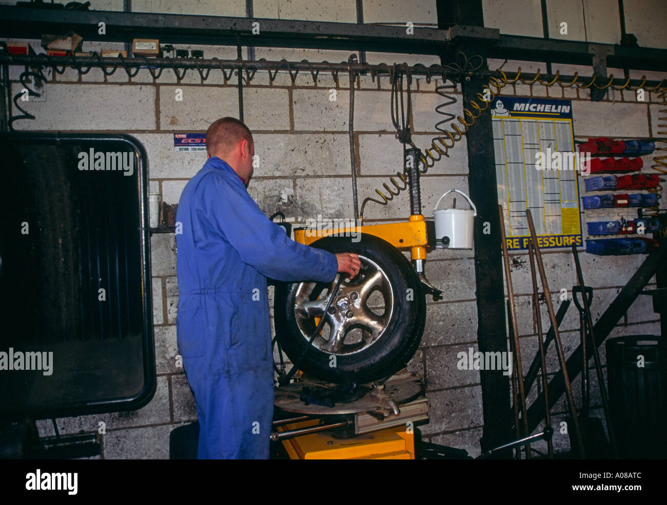 Mechanic fitter repairing tyre puncture in garage workshop Stock Photo ...
