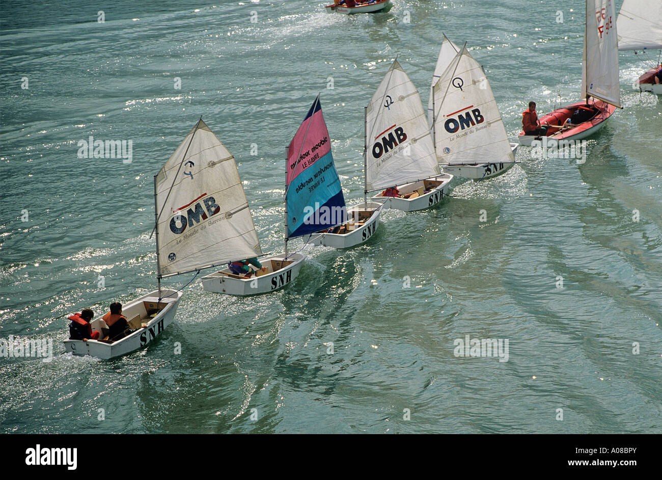 Children learning to sail in a train of sailboats all joined together ...