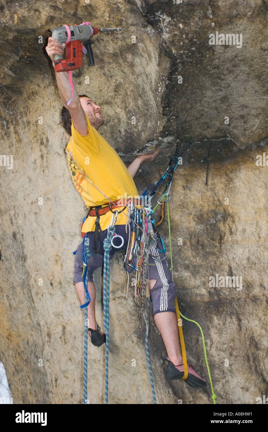 Rock Climber placing a protection bolt with battery powered power drill ...