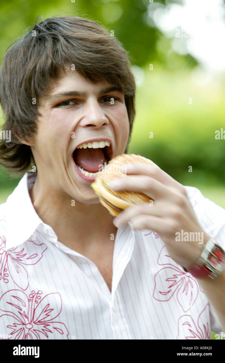 Junger Mann isst einen Hamburger, Young man eating hamburger Stock ...
